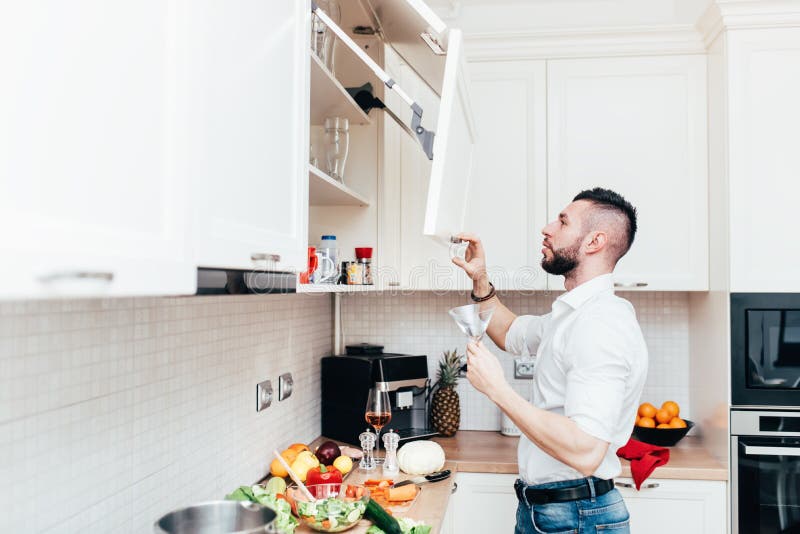Handsome Man Cooking and Drinking in New Kitchen, Preparing Glasses ...