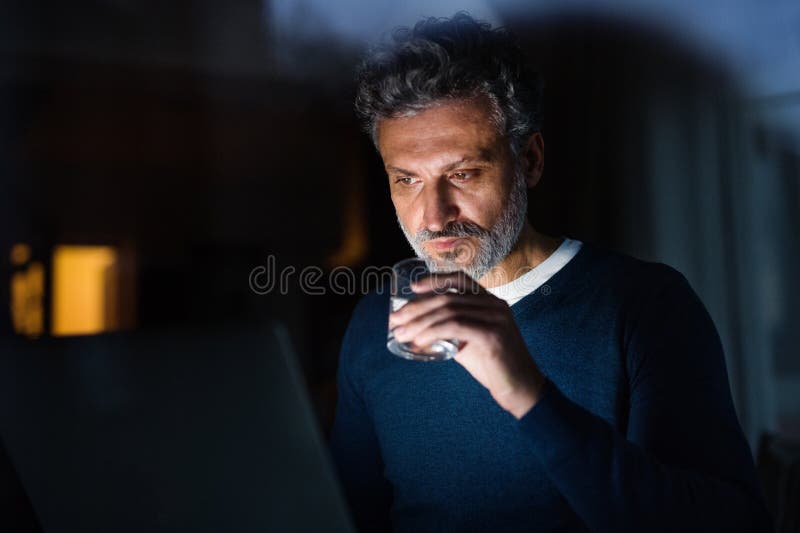 Handsome Man Drinking while Working from Home Office at Evening, Using ...