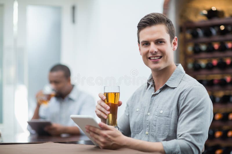 Handsome Man Holding Beer Glass while Using Digital Tablet Stock Photo ...