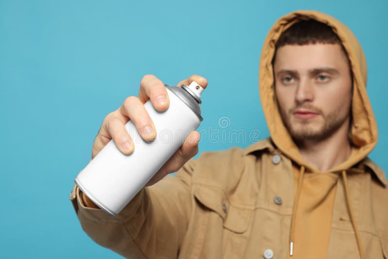 Handsome Man Holding White Spray Paint Against Light Blue Background ...