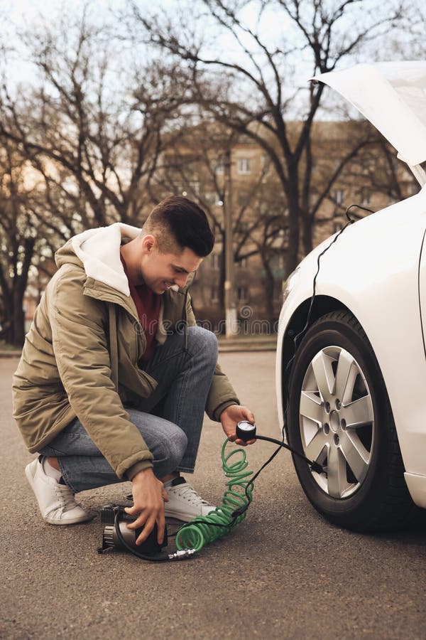 Handsome Man Inflating Car Tire with Air Compressor on Street Stock ...