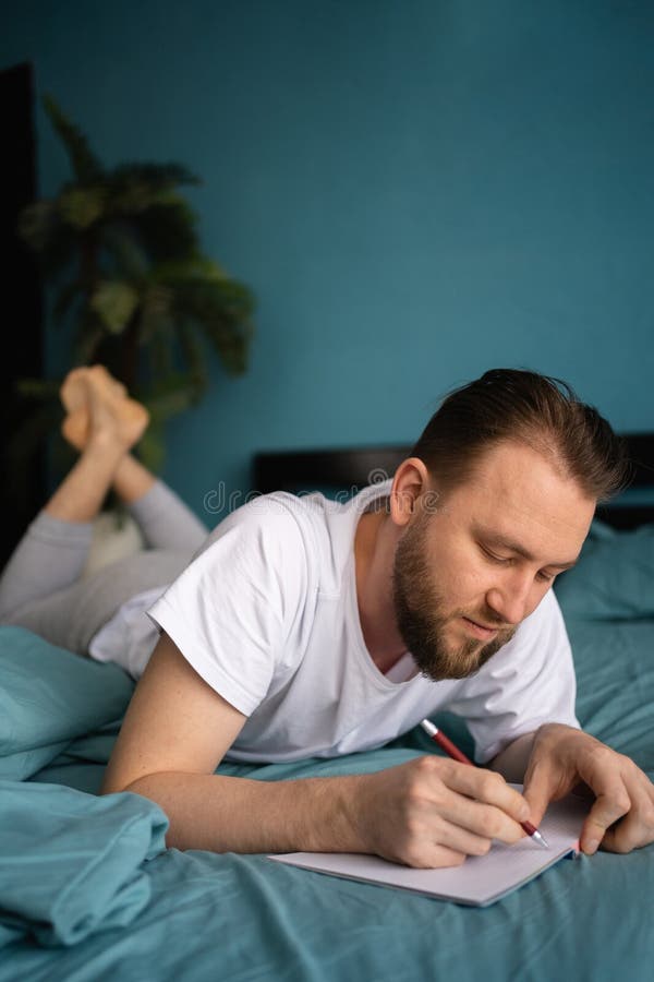 Handsome Man Laying on Bed and Writing a Diary Using Notebook and Pen ...