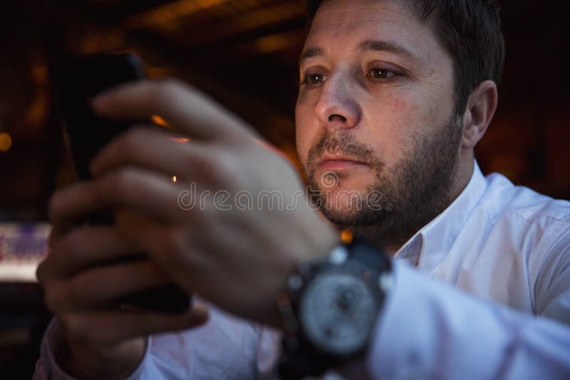 Man Looking at Smartphones Screen in the Dark Ambient while Sitting in ...