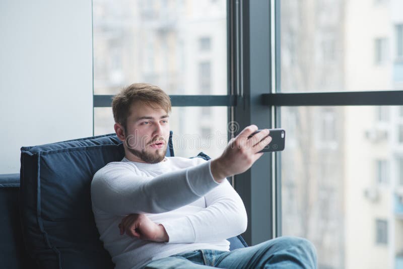 Man Makes a Salf Lying on the Couch at the Window. Man Makes a Sephi on ...