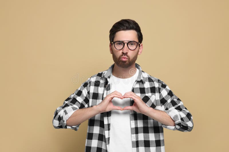 Handsome Man Making Heart with Hands and Blowing Kiss on Beige ...