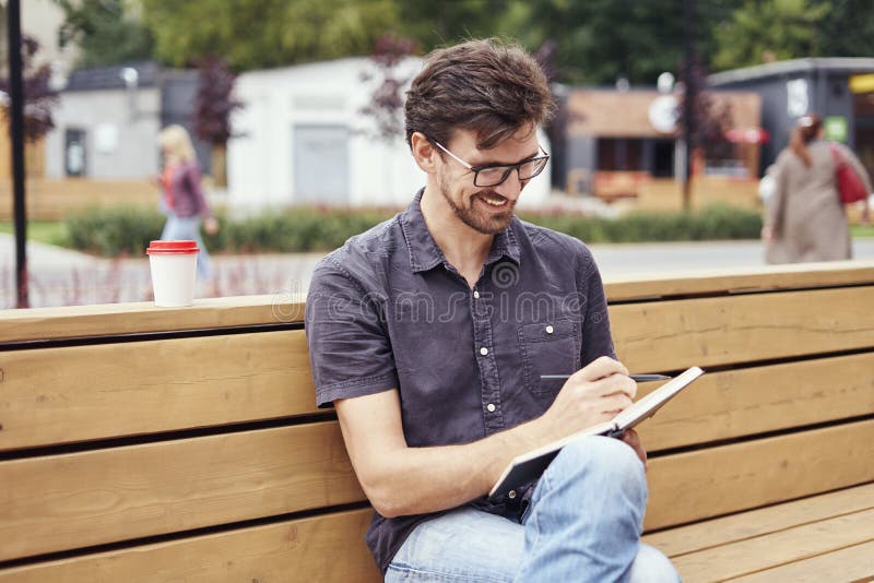 Handsome Man Making Notes in a Book Sitting Outside. Smiling Face ...