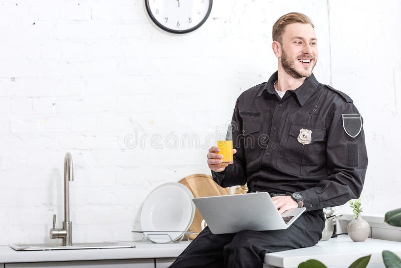 Handsome Man in Police Uniform Sitting on Kitchen Table, Drinking ...