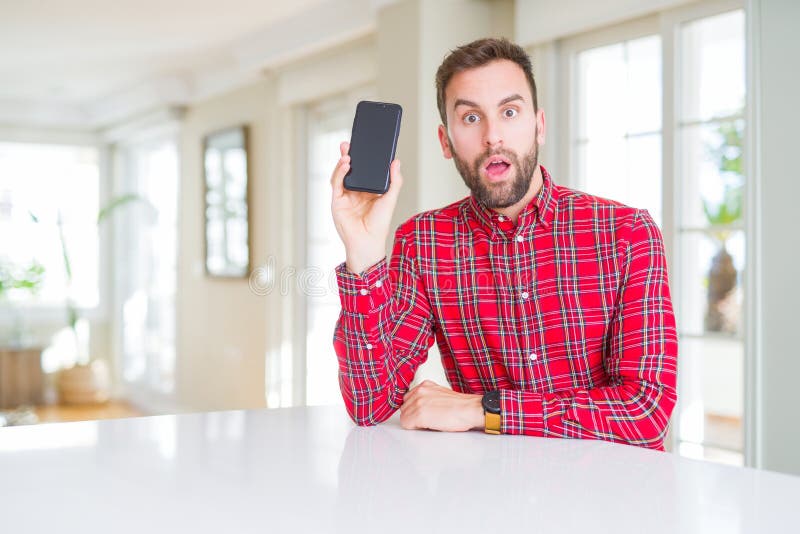Handsome Man Showing Smartphone Screen Scared in Shock with a Surprise ...