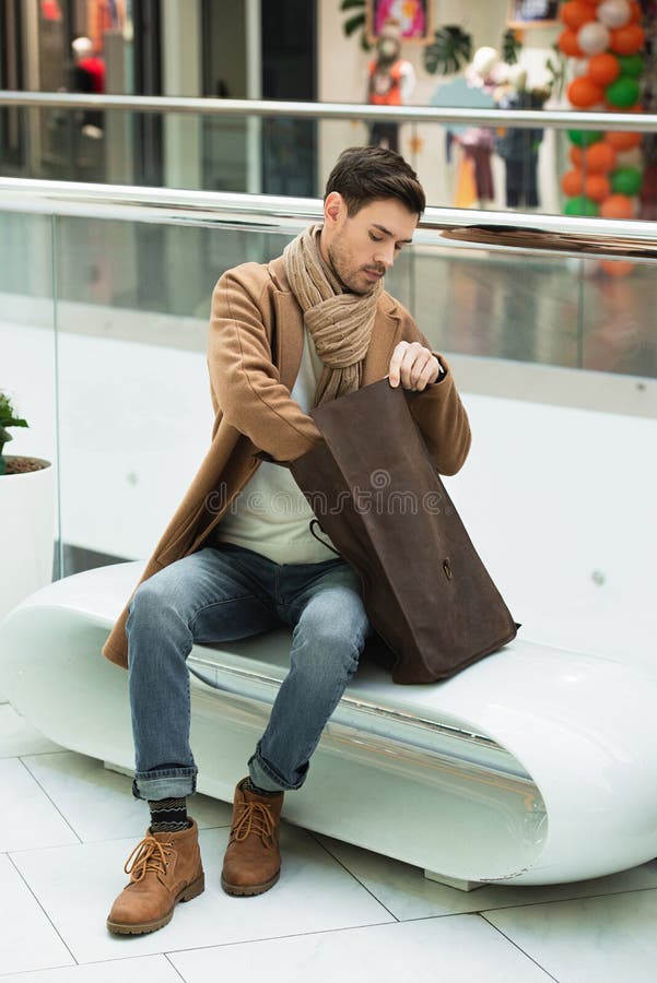Handsome Man Sitting on Bench and Holding Bag in Stock Photo - Image of ...