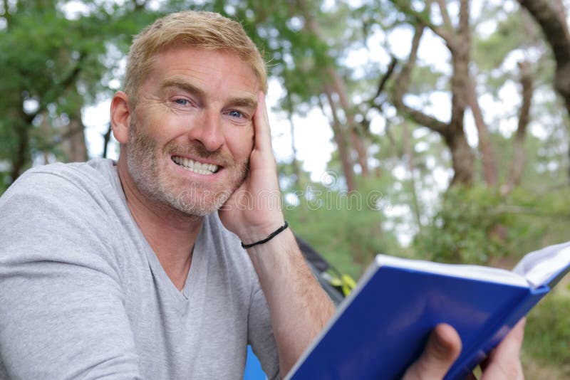 Handsome Man Sitting and Reading Book in Forest Stock Image - Image of ...