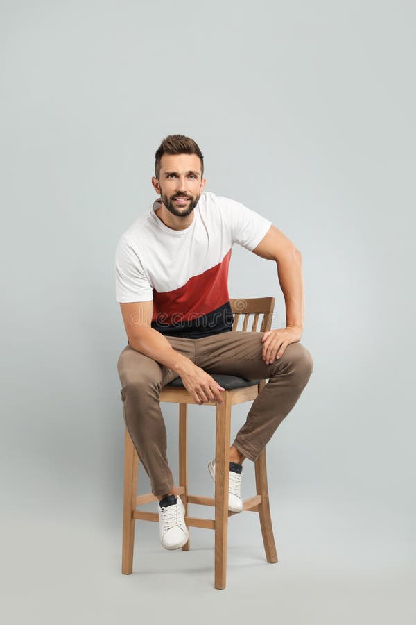 Handsome Man Sitting on Stool Against Light Grey Background Stock Photo ...
