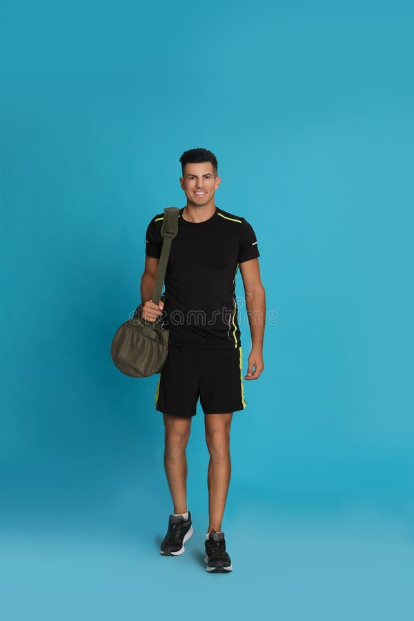 Handsome Man with Sports Bag on Light Blue Background Stock Photo ...