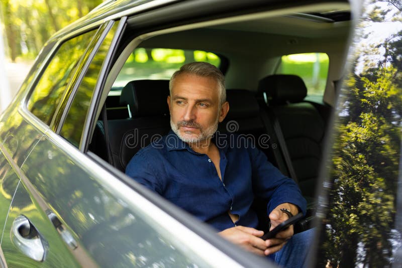 Handsome Man in Suit is Using a Smart Phone and Smiling while Sitting ...
