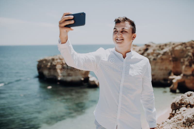 Handsome Man Taking A Selfie On Vacation On Ocean And Cliff Background