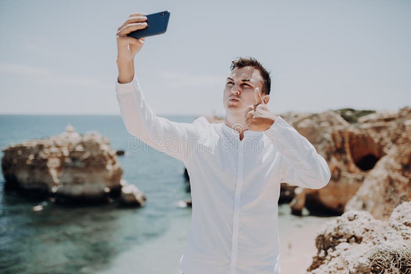 Handsome Man Taking A Selfie With Thumbs Up At Cliff Ocean Beach Stock