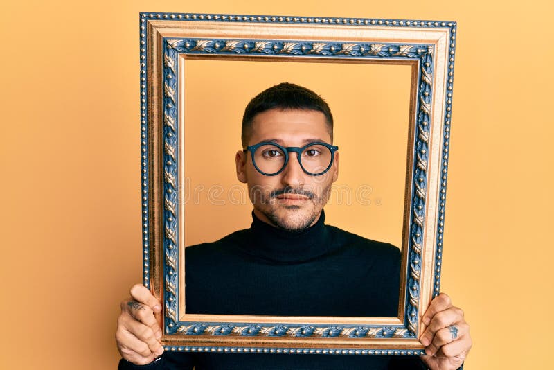 Handsome Man with Tattoos Holding Empty Frame Relaxed with Serious ...
