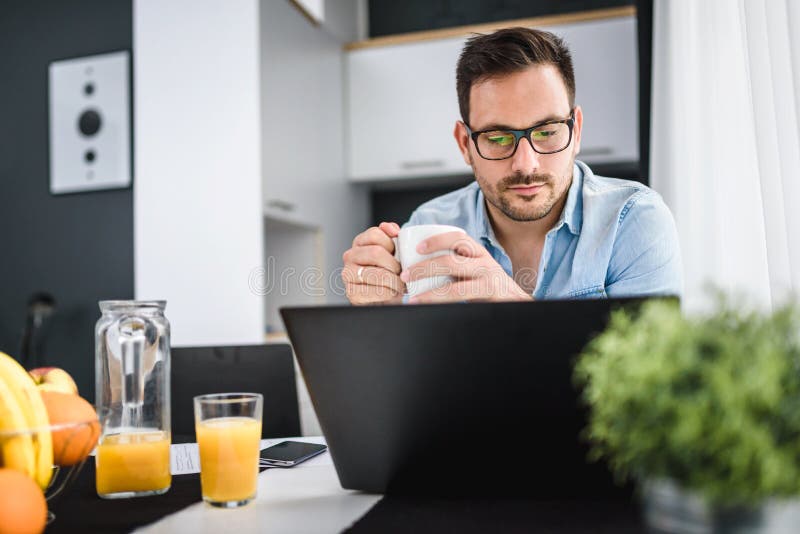 Handsome Man Using Laptop Computer at Home, Drinking Juice and Coffee ...