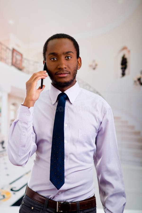 Handsome Man Wearing Shirt And Tie Standing In Lobby Area Talking On