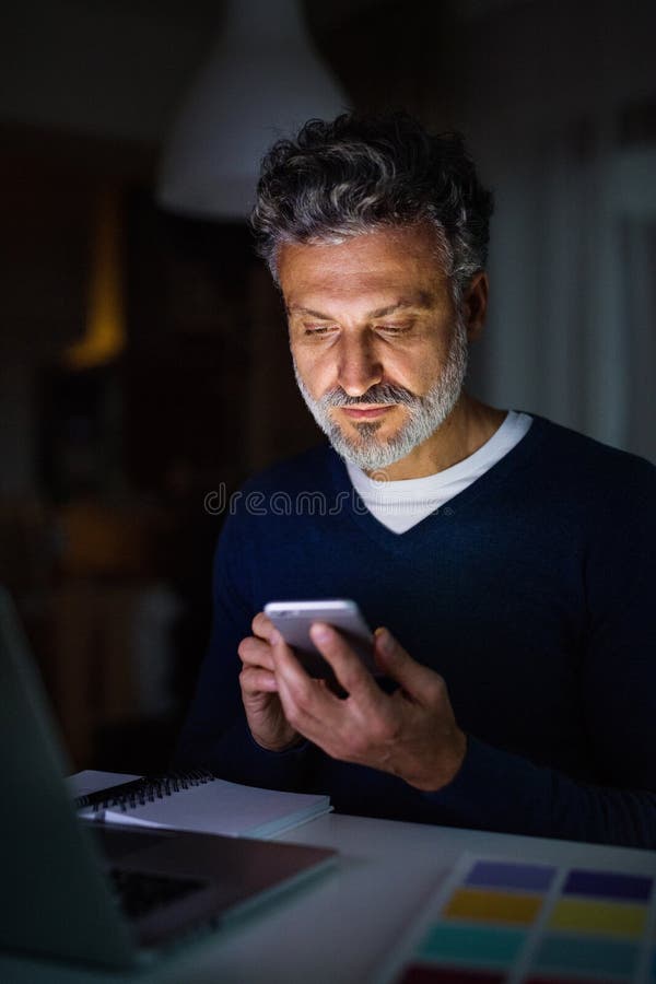 Handsome Man Working from Home Office at Evening, Holding Smartphone ...