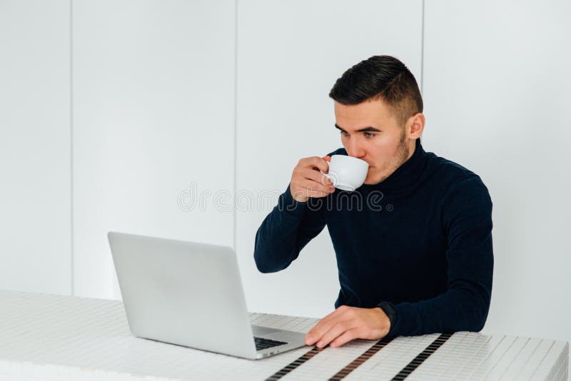 Serious Man Drinking Tea while Working with a Laptop at Home Stock ...