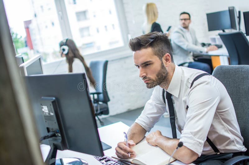 Handsome Man Writing Notes on a Writing Pad while Sitting at His Desk ...