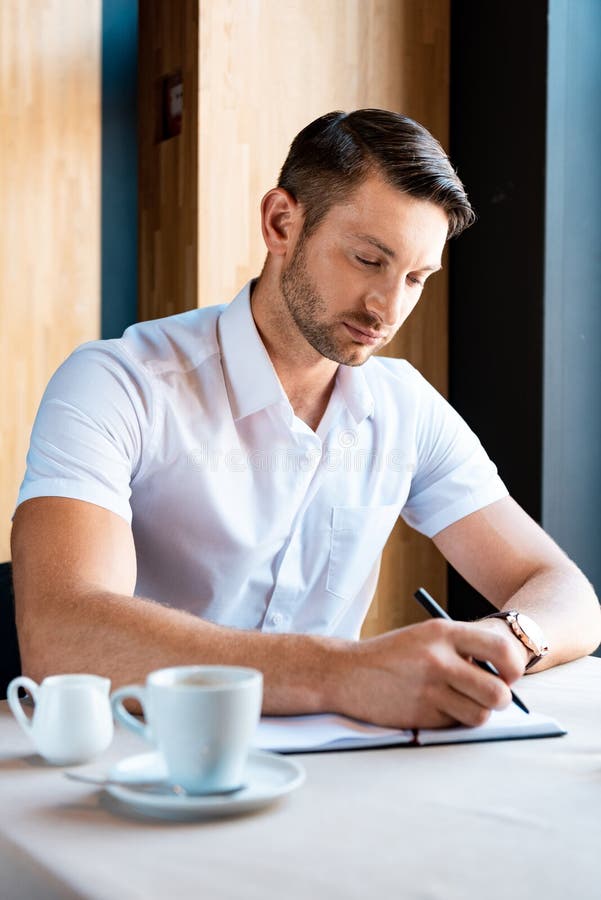Handsome Man Writing in Textbook in Cafe Stock Photo - Image of ...