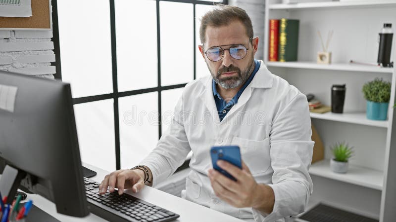 Handsome Mature Hispanic Man in a Lab Coat Works at a Computer in a ...