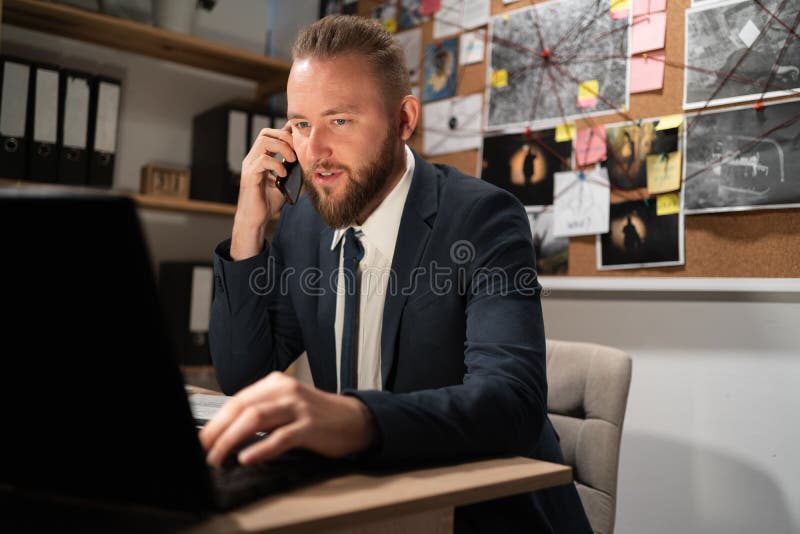 Handsome Police Officer Sitting beside Computer, Talking on a Cell ...