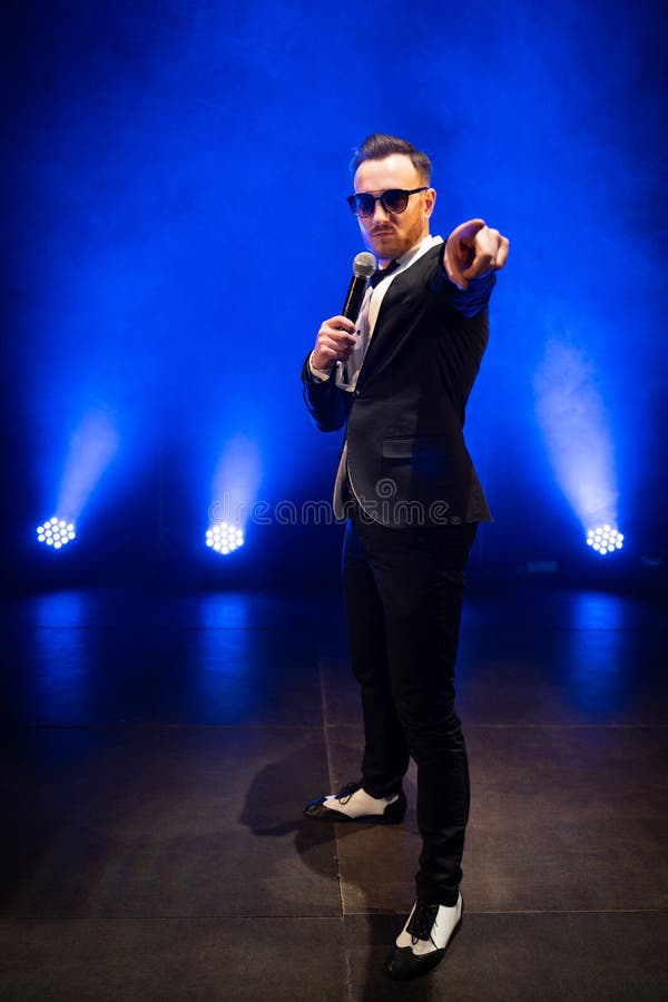 Handsome Presenter and Showman in a Stylish Suit with a Microphone on ...