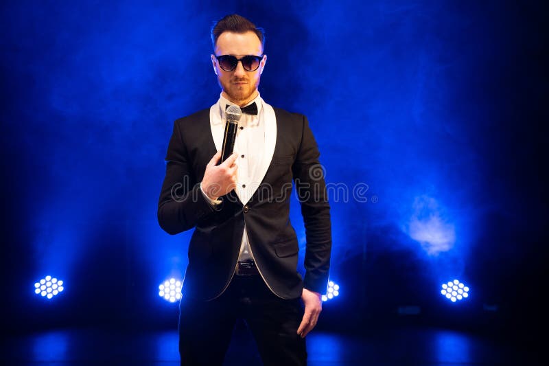 Handsome Presenter and Showman in a Stylish Suit with a Microphone on ...