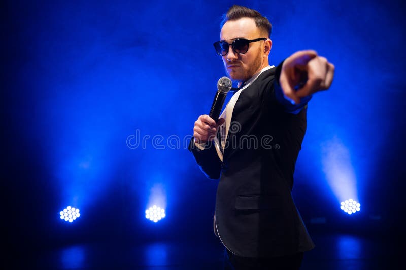 Handsome Presenter and Showman in a Stylish Suit with a Microphone on ...
