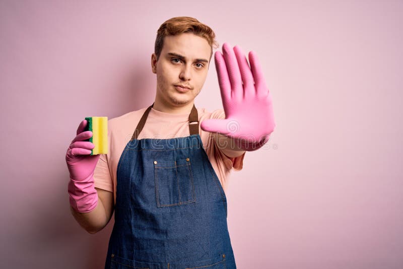 Handsome Redhead Man Doing Housework Wearing Apron And Gloves Using Cleaner Scourer With Open