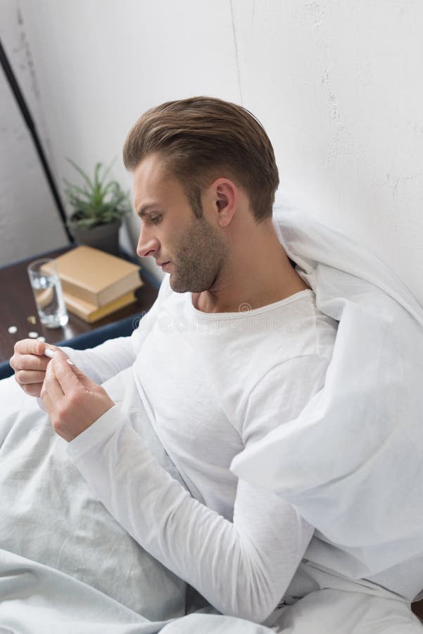Handsome Sick Man Looking at Thermometer while Stock Image - Image of ...