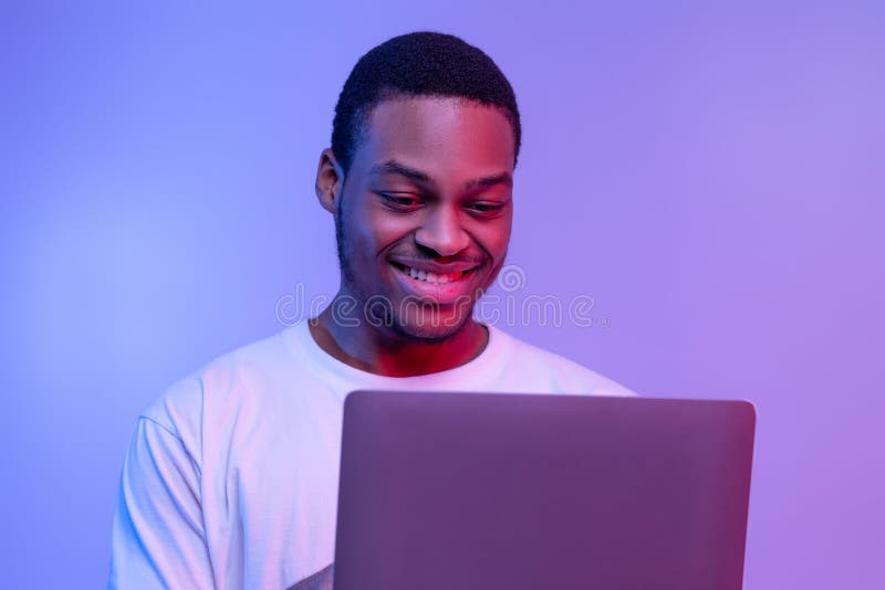 Handsome Smiling Black Programmer Guy Working Online on Laptop in Neon ...