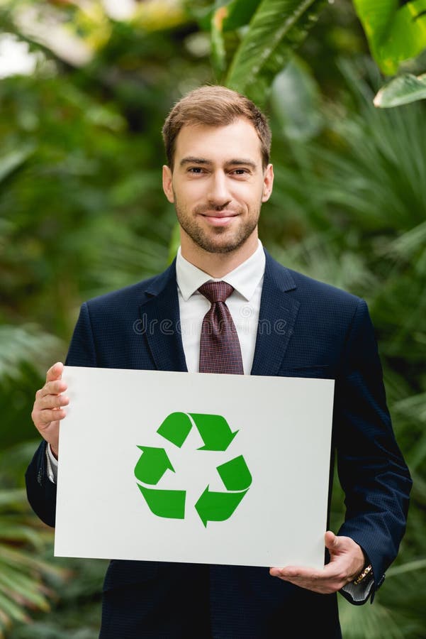Handsome Smiling Businessman in Suit Holding Card with Green Recycling ... Handsome Smiling Businessman in Suit Holding Card with Green Recycling ...