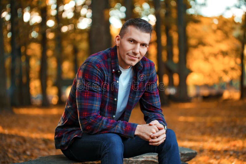 Handsome Smiling Man Sitting on a Bench in the Autumn Park Stock Photo ...