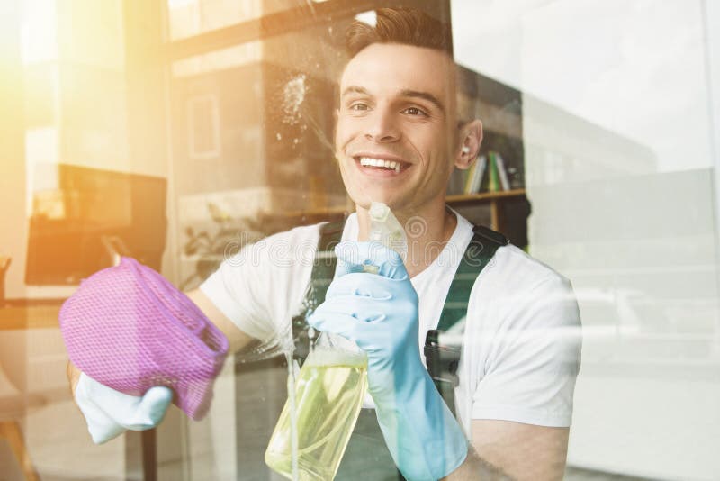 Handsome Smiling Young Man Cleaning and Wiping Window with Spray Bottle ...