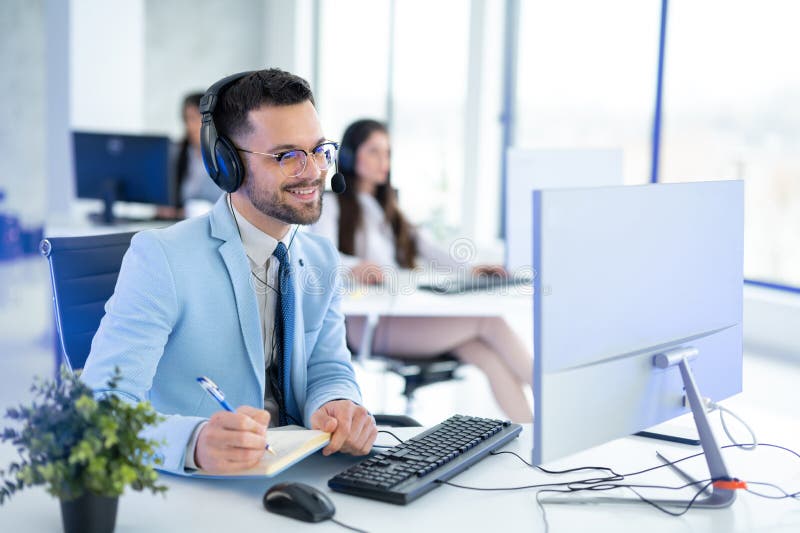 Handsome Support Specialist Agent Man Taking Notes while Having Online ...