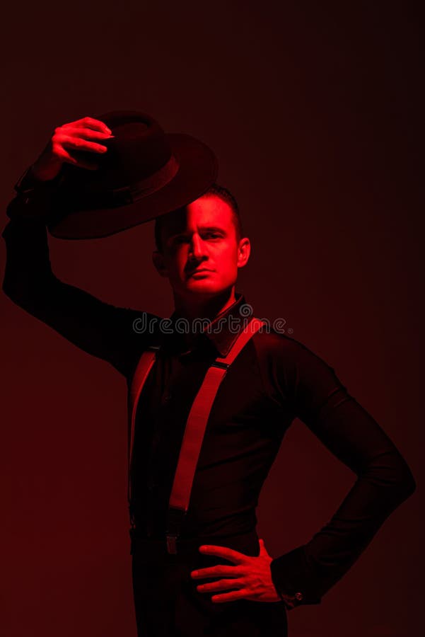 Tango Dancer Looking at Camera and Holding Hat Above Head on Dark ...