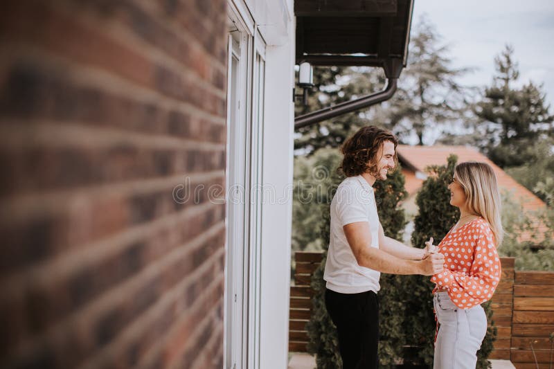 Smiling Young Couple in Love Dancing in Front of House Brick Wall Stock ...