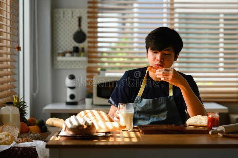 Handsome Young Asian Man Eating a Slice of Bread with Jam for Breakfast ...