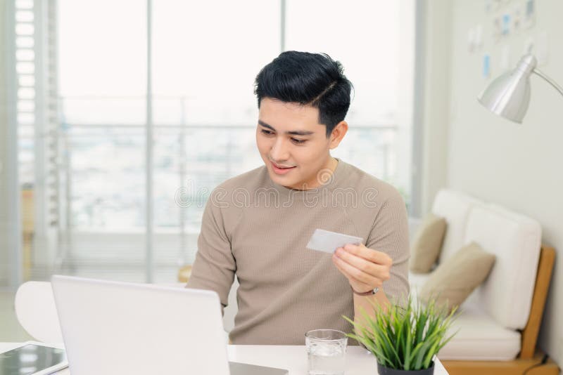 Handsome Young Businessman Using a Computer while Holding a Credit Card ...