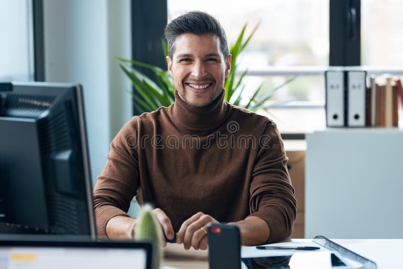 Handsome Young Entrepreneur Looking at Camera while Using the Computer ...