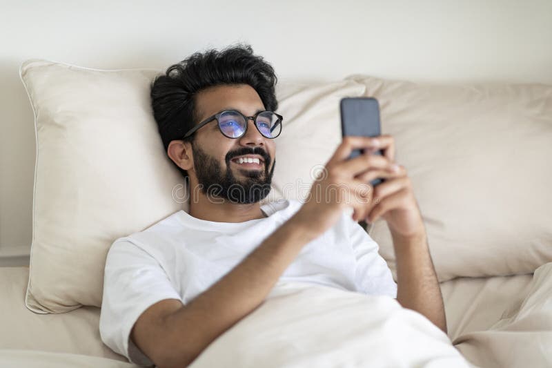 Handsome Young Indian Man Using Smartphone while Lying in Bed Stock ...