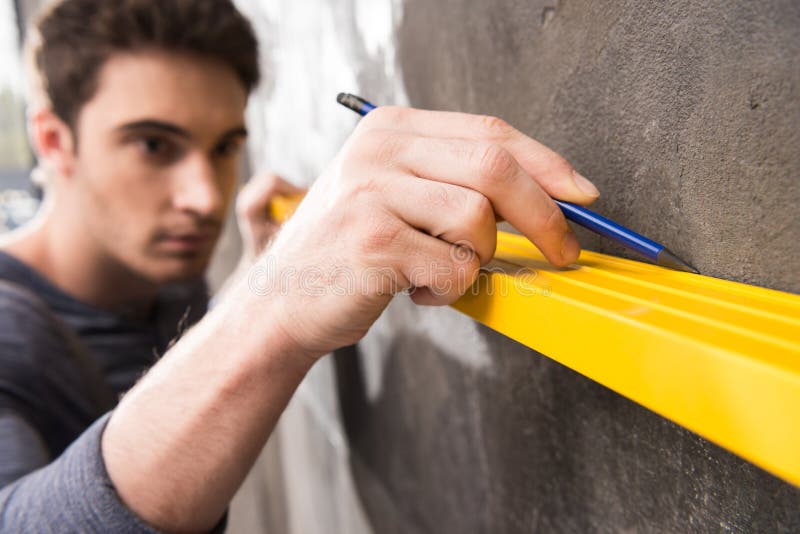 Handsome Young Laborer with Pencil Measuring Wall with Level Tool Stock ...