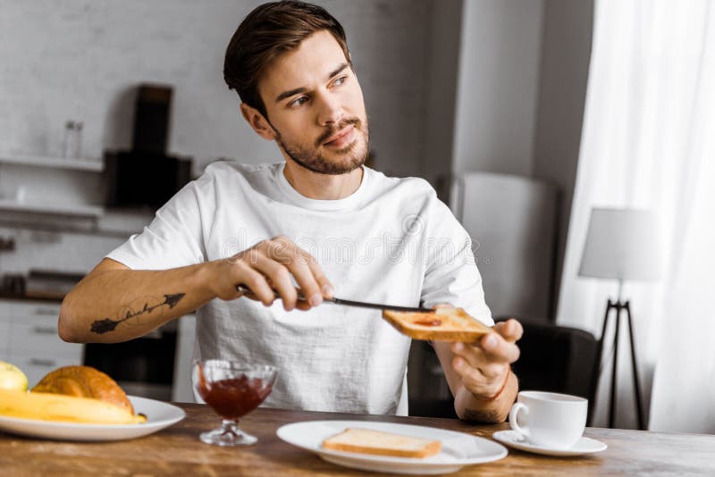 Handsome Young Man Applying Jam Onto Toast Stock Photo - Image of ...