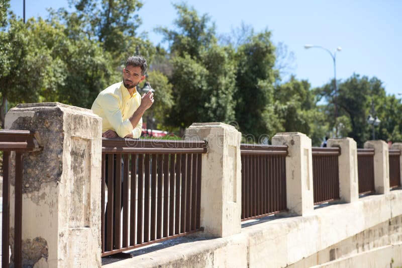 A Handsome Young Man with a Beard and Sunglasses in His Hand is Leaning ...