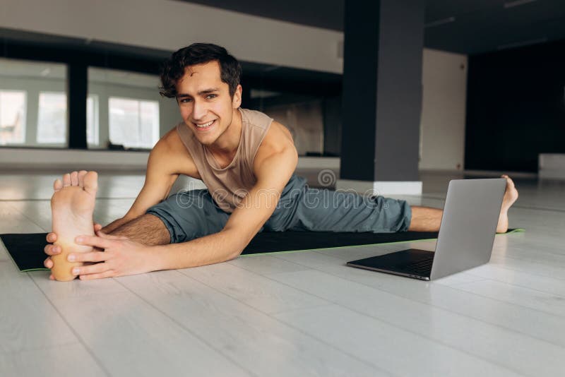 Handsome Young Man Doing the Splits while Watching Tutorials. Guy ...