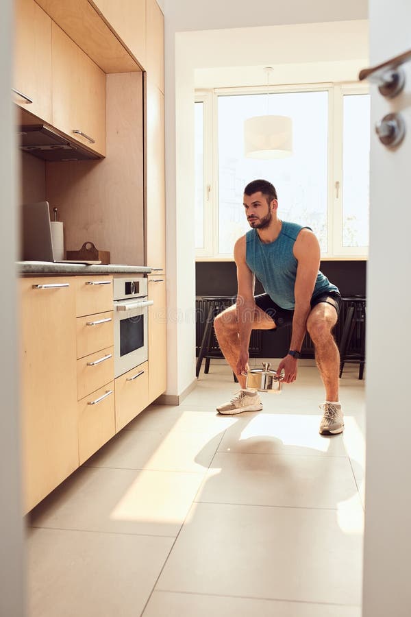 Handsome Young Man Doing Squats with Cooking Pot in Kitchen Stock Photo ...