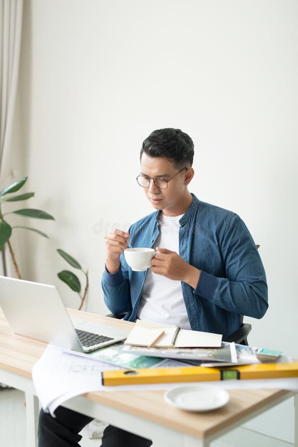 Handsome Young Man Drinking Coffee and Working at His Desk at the ...